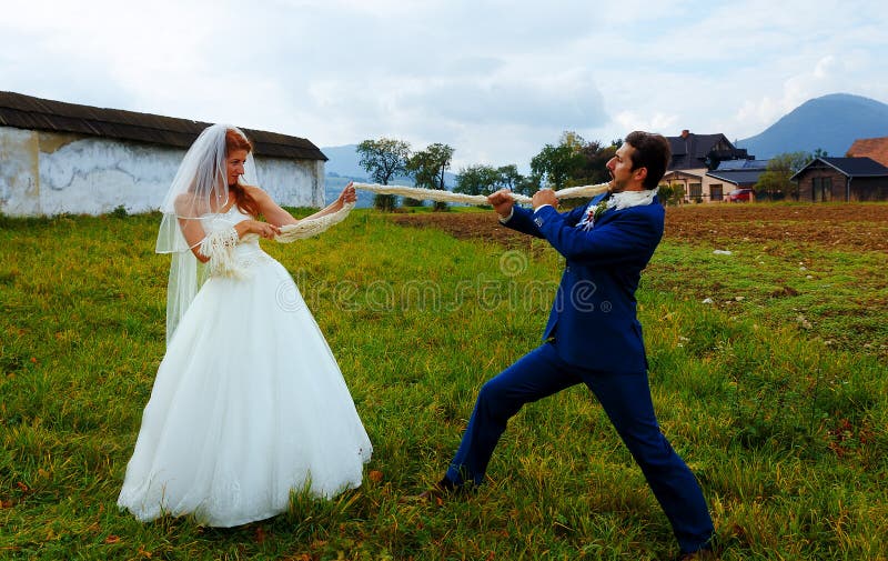 Bride Pulling Her Groom To Her with a Rope - Funny Wedding Concept ...