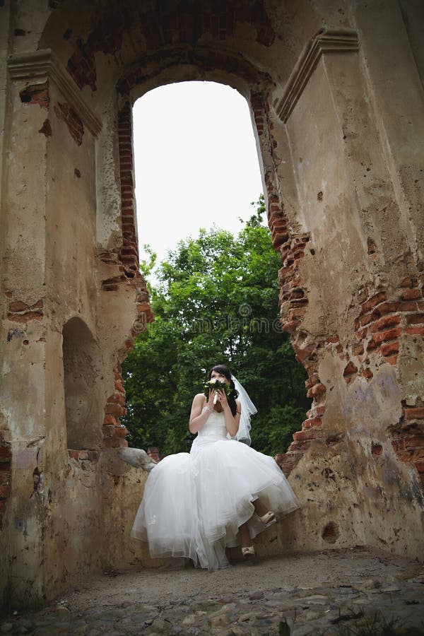 The Bride is Sitting on the Ruins and Holding a Wedding Bouquet Stock ...