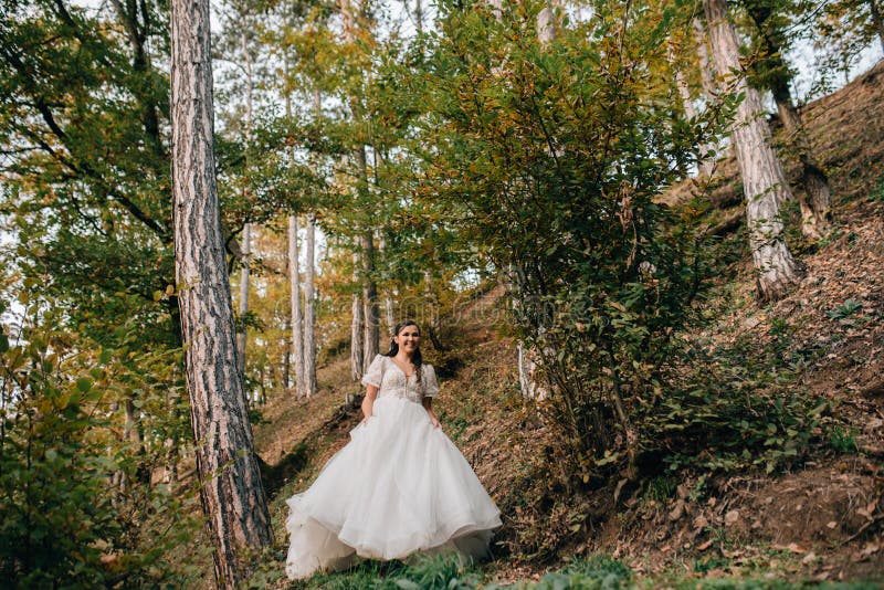Bride Walking through Forest in Her Wedding Dress. Stock Photo - Image ...