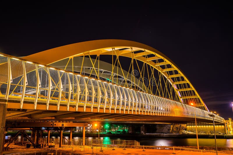 Bridge in a City with a Large Yellow Arch on Top at Nighttime Editorial ...