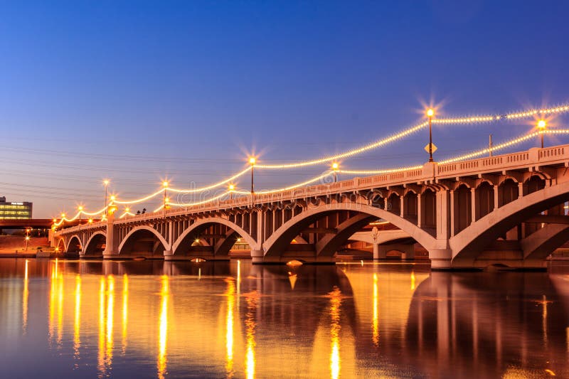 A Bridge with Lights Hanging from it Over a River Stock Image - Image ...