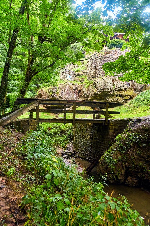 Bridge Over Creek with Stone Wall and Structure on Cliff in Green ...