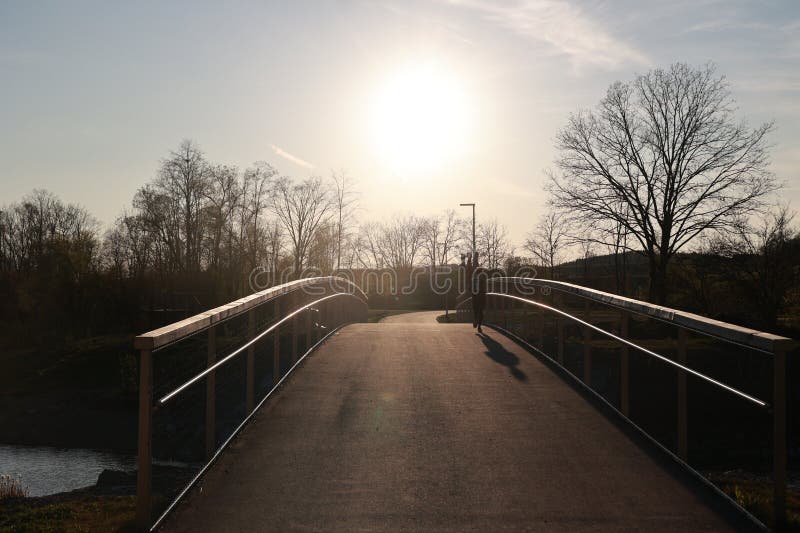 A Bridge Over a River with a Person Walking Across it Stock Image ...