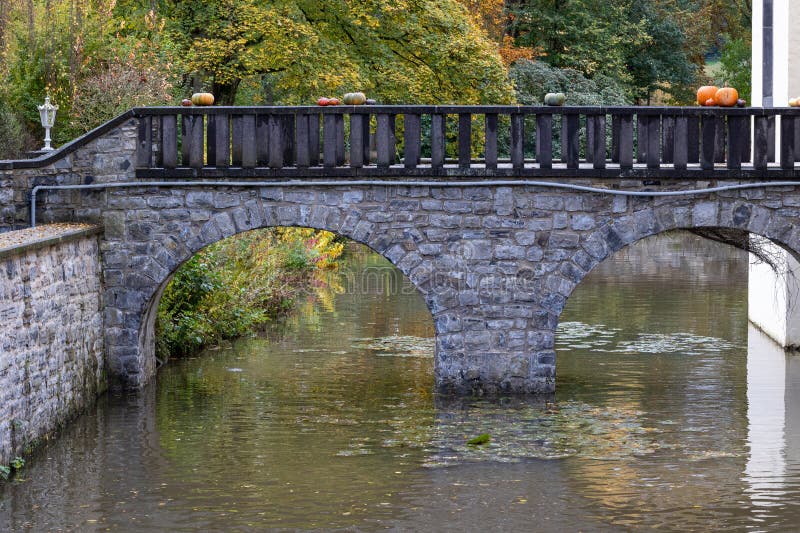 A Bridge Over a River with a Stone Arch and a Few Pumpkins on it Stock ...