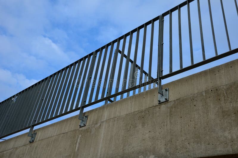 A Bridge Railing with Vertical Fence Posts Anchored into the Ground ...