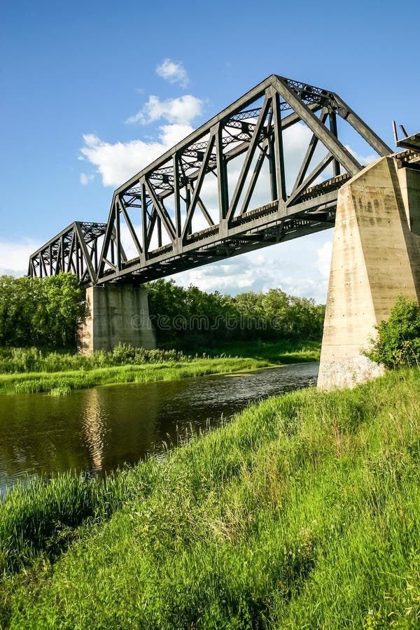 A Bridge Spans a River with a Green Grassy Bank Stock Photo - Image of ...