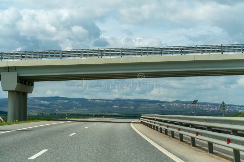 A Bridge Spans a Road with a Clear Sky Above. the Bridge is a Large ...