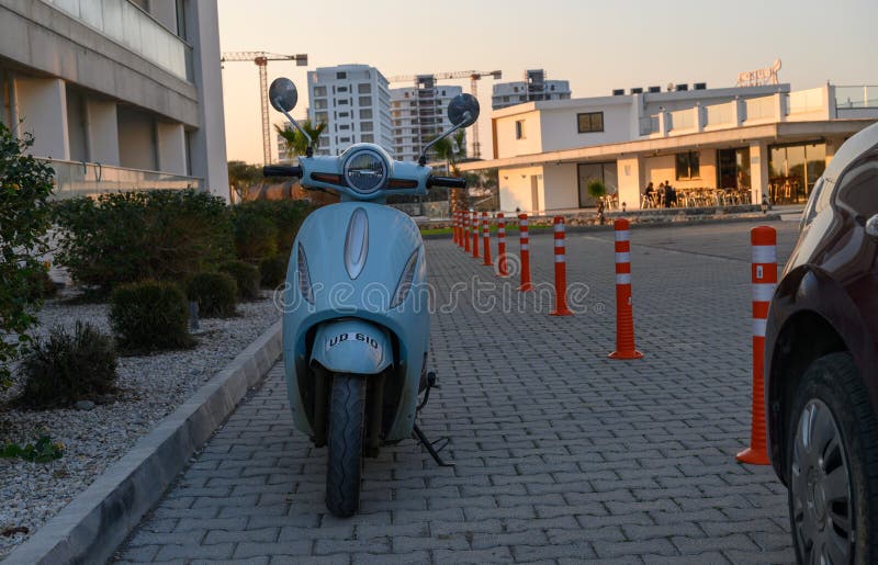 Bright Blue Scooter Parked Along a Stylish Pathway at Sunset in a ...