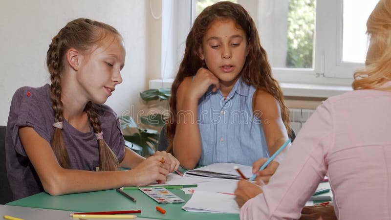 Two Schoolgirls Engaged in a Lively Art Class with Their Teacher Stock ...