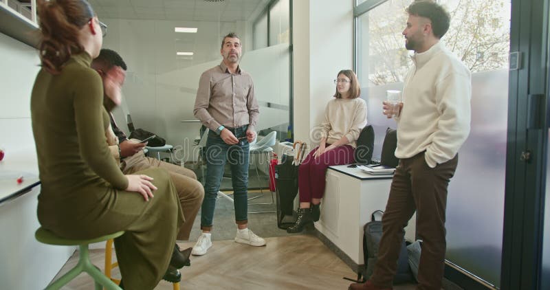 A Multiethnic Group of Colleagues Engages in a Relaxed Discussion while ...