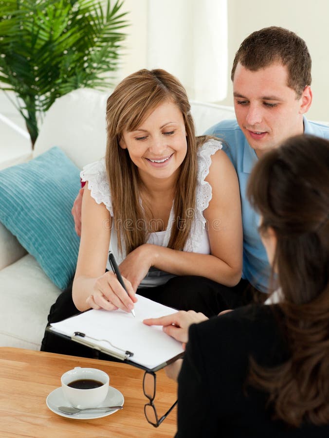 Bright Couple Signing a Contract Sitting on a Sofa Stock Image - Image ...