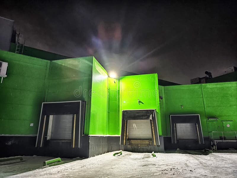Bright Green Warehouse Illuminated at Night with Loading Docks and ...