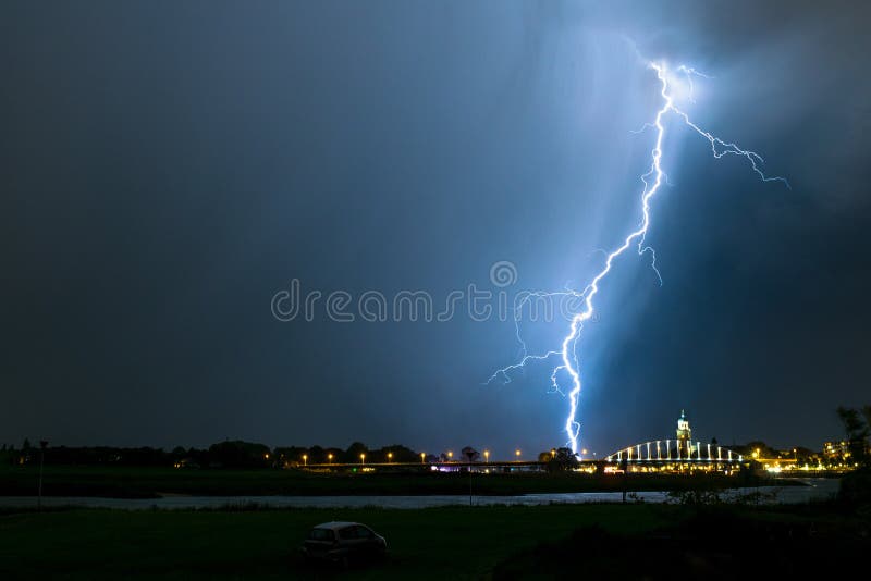Forked Lightning Strikes Down from a Thunderstorm Close To a Bridge in ...