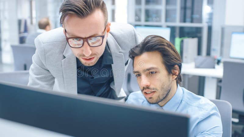 In Bright Modern Office: Handsome Office Worker Sitting and Working at ...