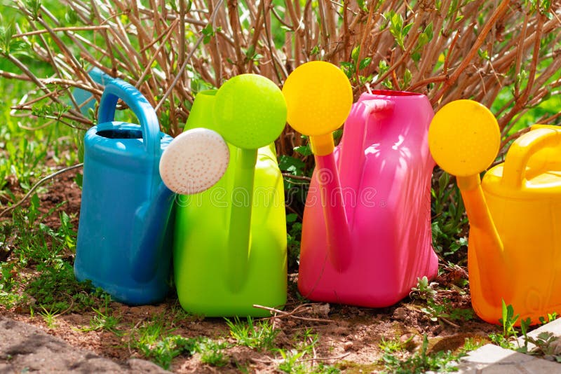 Bright Multi-colored Plastic Watering Cans in the Spring Garden. Stock ...