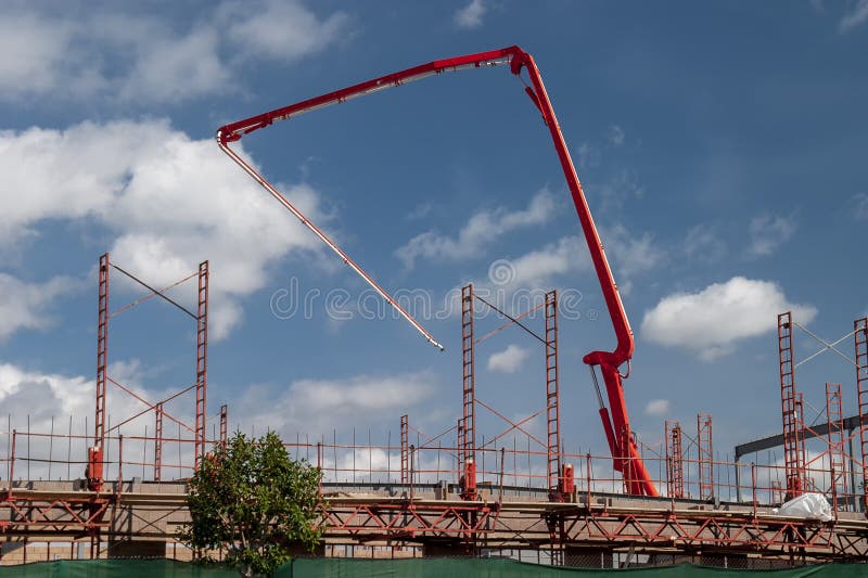 A Bright Orange Cement Crane Pump at a Construction Site Against a Blue ...