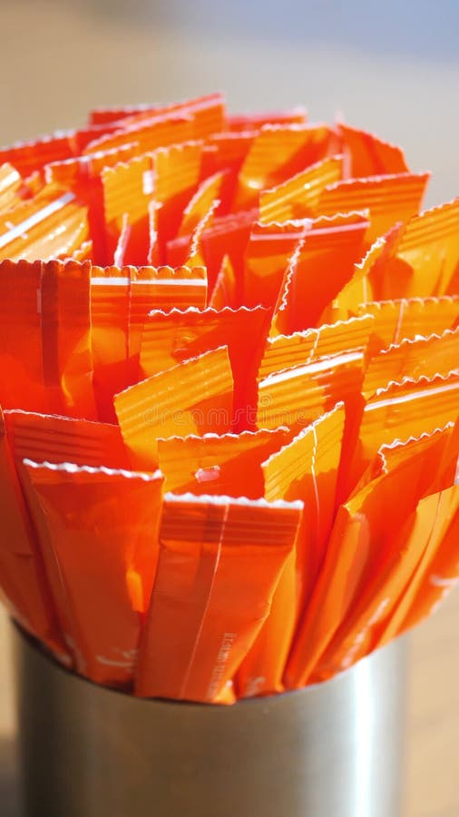 Bright Orange Sugar Wrappers in a Container on a Wooden Table Stock ...
