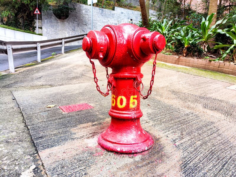 A Bright Red Fire Hydrant Stands on a Concrete Sidewalk, with a Chain ...