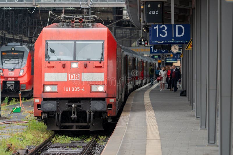 Bright Red Train Pulling into a Bustling Station As People Patiently ...