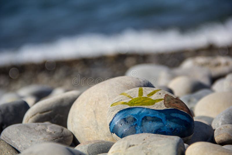 Bright Sun Painted on Pebble. Pebbles and Sea Background Stock Image ...