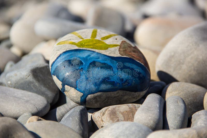 Bright Sun Painted on Pebble. Pebbles and Sea Background Stock Image ...
