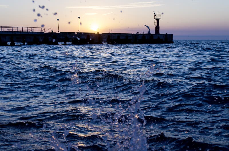Bright Sunset Under the Sea and Pier with Waves Splashes. Stock Photo ...