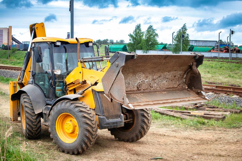 A Bright Yellow Bulldozer or a Loader is Parked on the Side of the Road ...