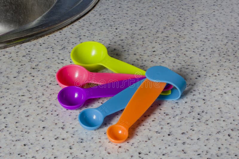 Bright Yellow Multicolored Plastic Measuring Spoons on a Gray Kitchen ...