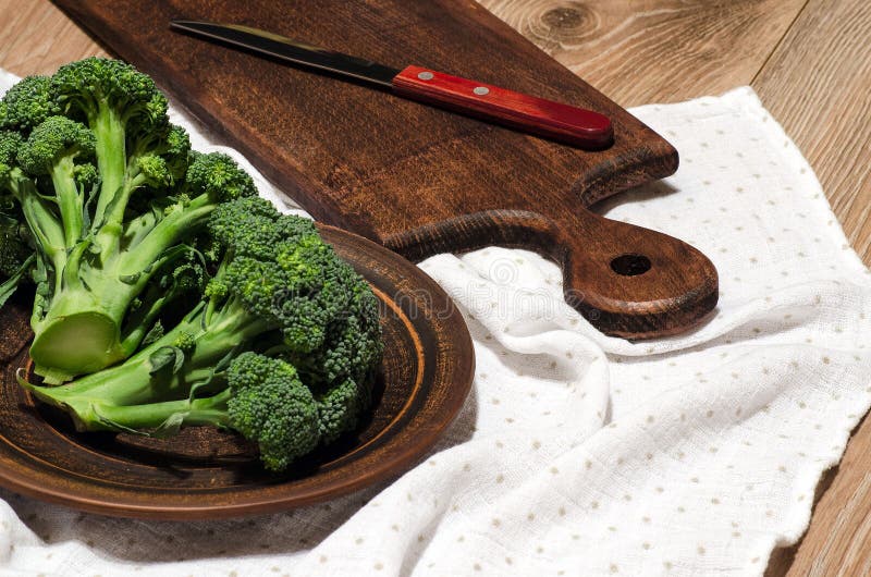 Broccoli on a Clay Plate, a Cutting Board and Knife Stock Photo - Image ...