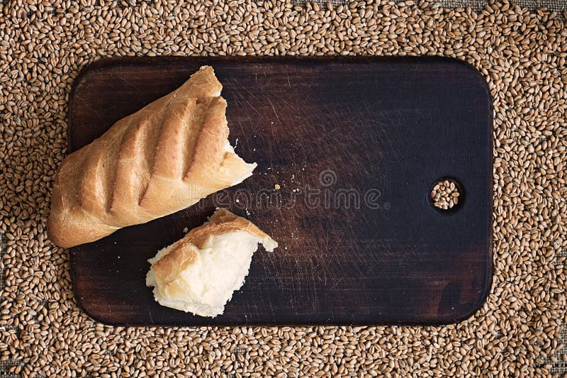 Broken Bread on a Kitchen Board Against a Background of Wheat Grains ...