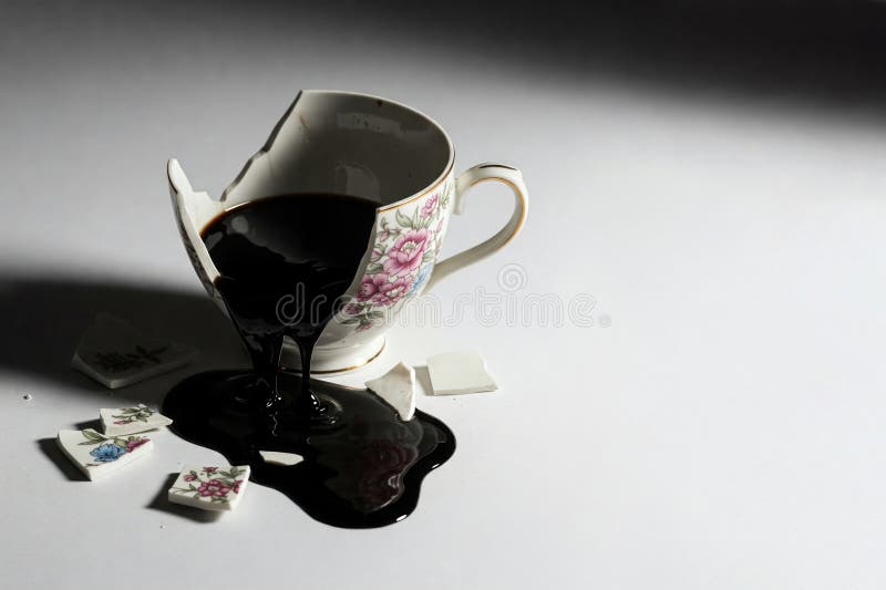 A Broken Cup with a Black Liquid Flowing Onto a White Surface. Space ...