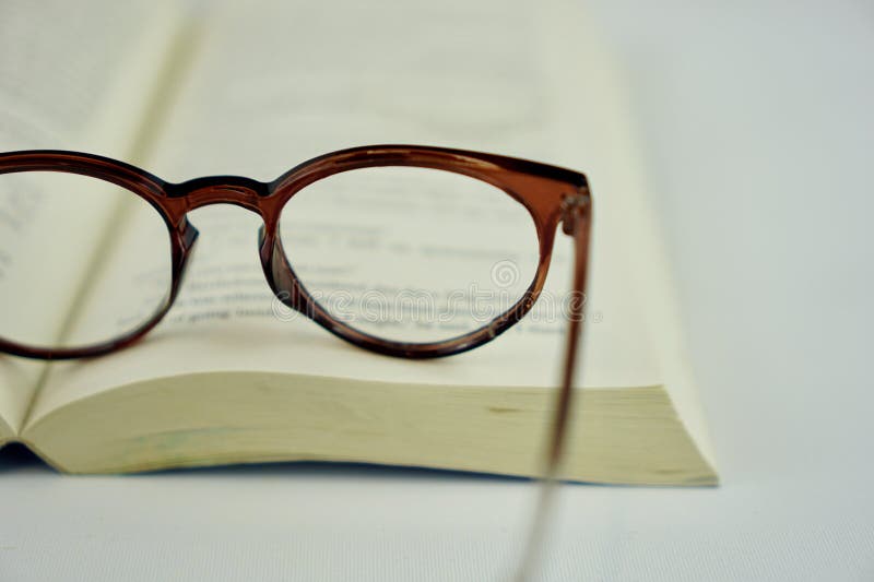 Broken Eyeglasses with Detached Lens Resting on an Open Book ...