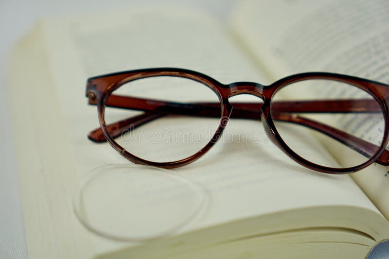 Broken Eyeglasses with Missing Lens Lying on an Open Book Representing ...