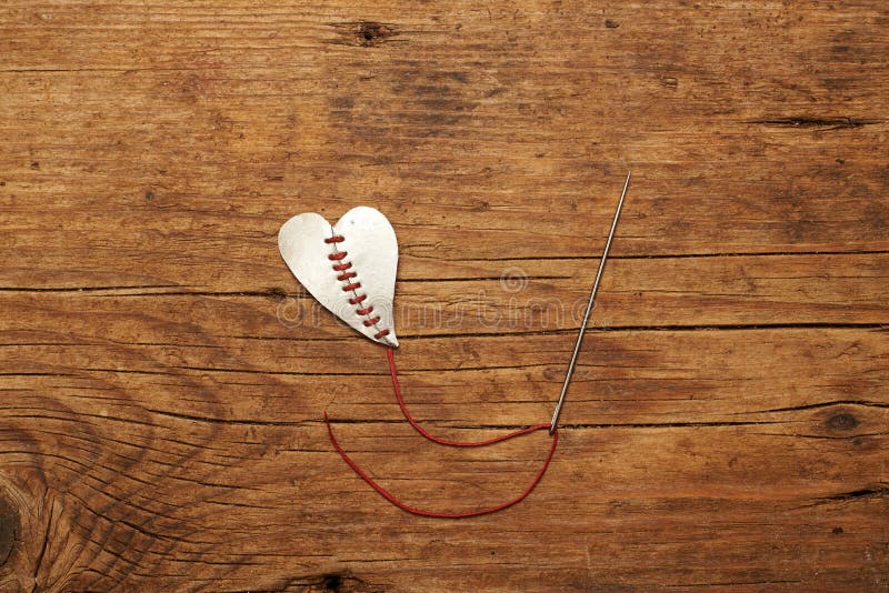 Broken Heart Stitched with Red Thread on a Wooden Table. Stock Image ...