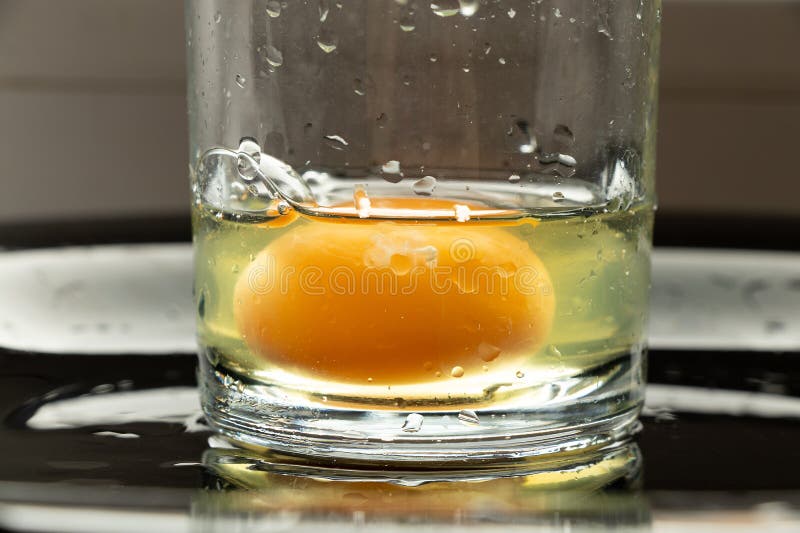 A Broken Raw Egg in a Glass Stands on a Black Flat Plate Close-up Stock ...