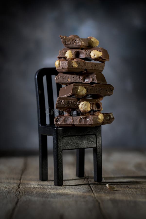 Broken and Stacked Hazelnut Chocolate on a Small Black Chair Stock ...