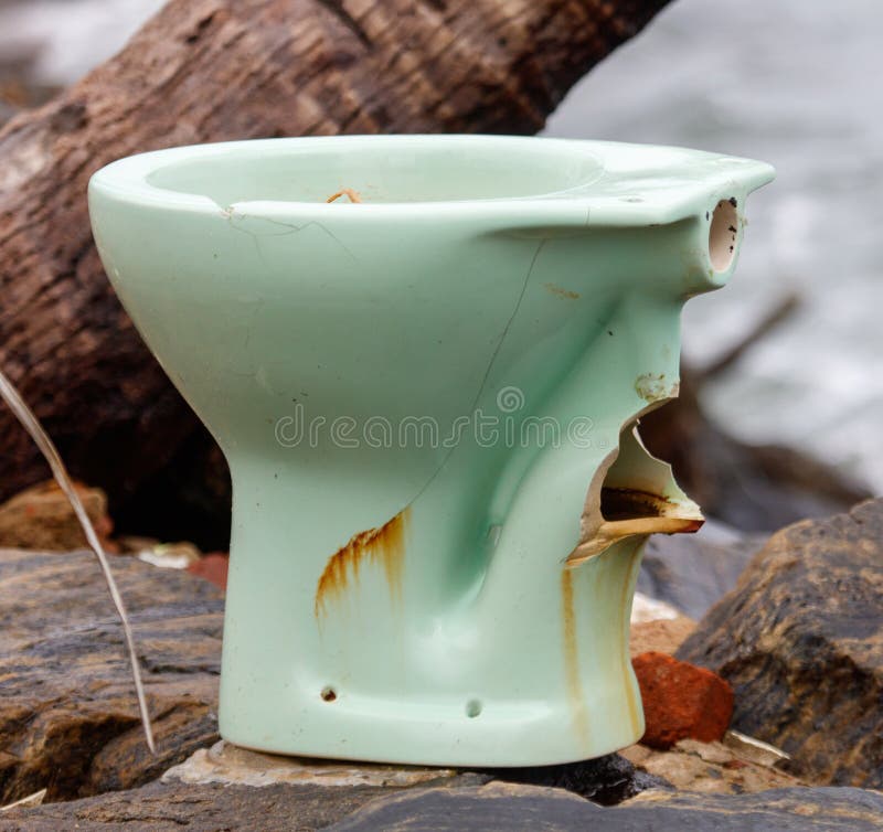 A Broken Toilet is Sitting on a Rock by the Water Stock Photo - Image ...