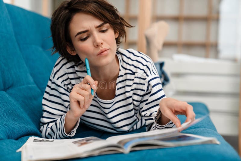 Brooding Beautiful Student Girl Doing Homework while Lying on Couch ...