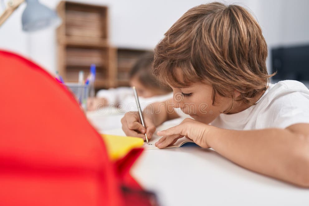 Brother and Sister Students Writing on Notebook Studying at Classroom ...