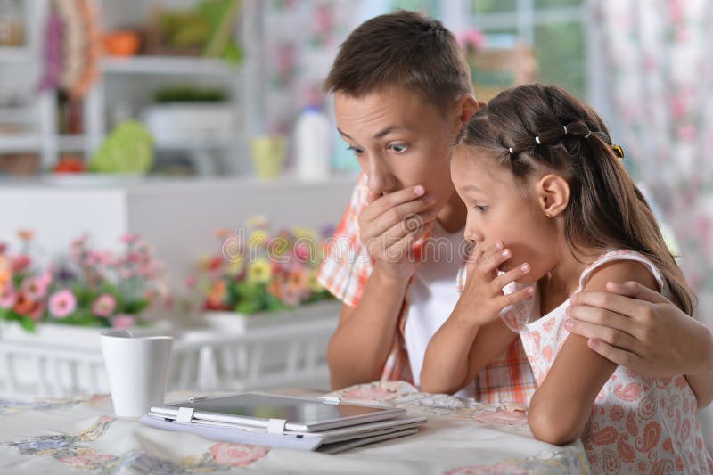 Brother and Sister Using Tablet Sitting at Table Stock Image - Image of ...