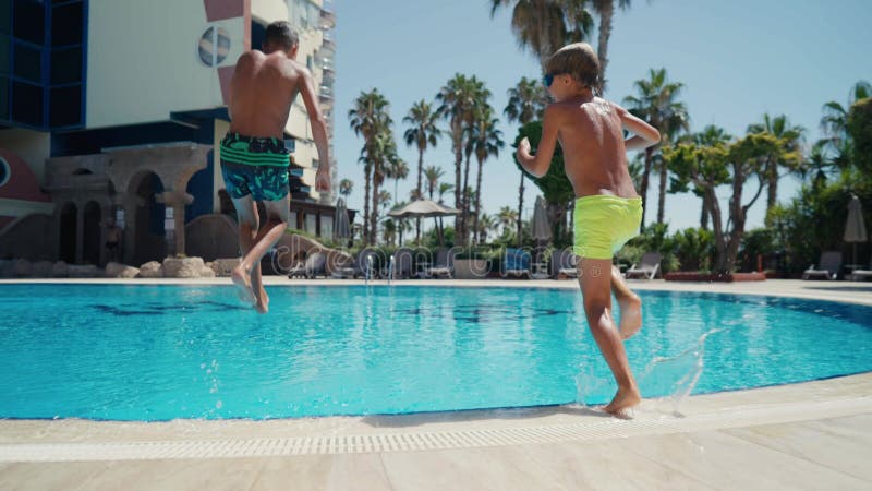 Brothers Jumping in the Water. Two Boys Fun Jumping into Swimming Pool ...