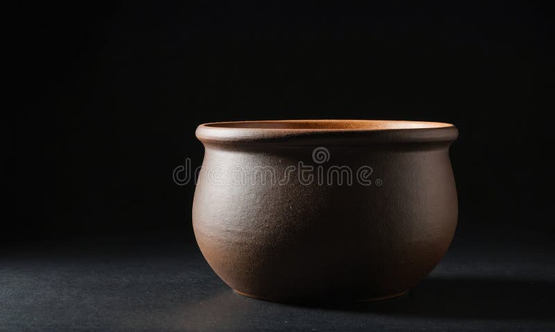 A Brown Ceramic Pot Sits on a Dark Surface in a Studio Setting Stock ...