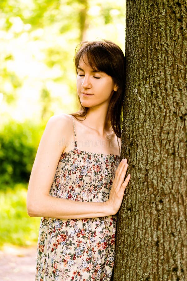 A Brown Haired Nature Lover Girl Hugs A Huge Tree Trunk In The Park