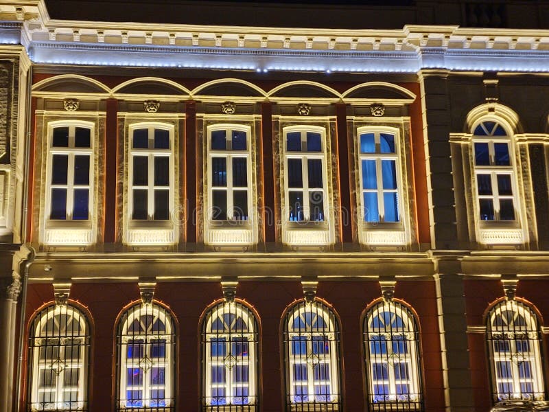 Brown House Facade with Illuminated Elongated Windows Divided into ...