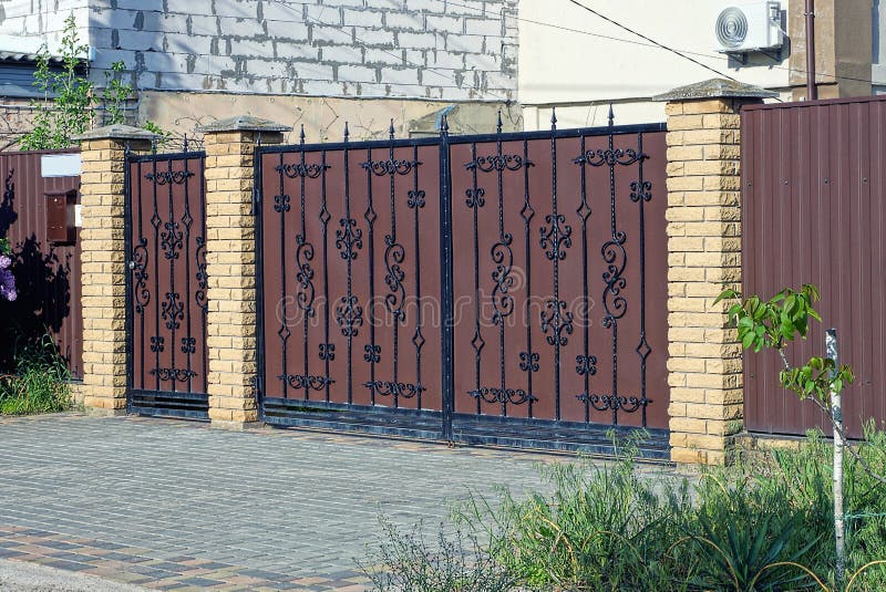 Brown Metal Gate with a Pattern and a Brick Fence Stock Image - Image ...