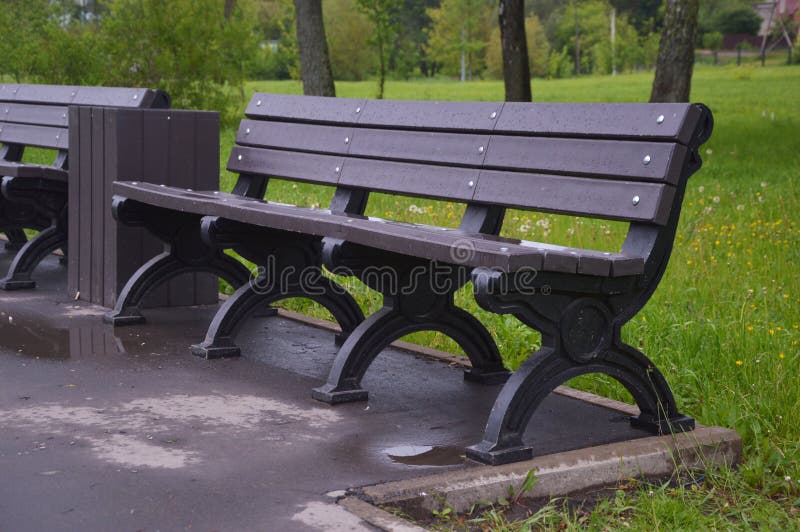 Brown Wooden Bench in the Park with a Trash Can on the Path, Front View ...