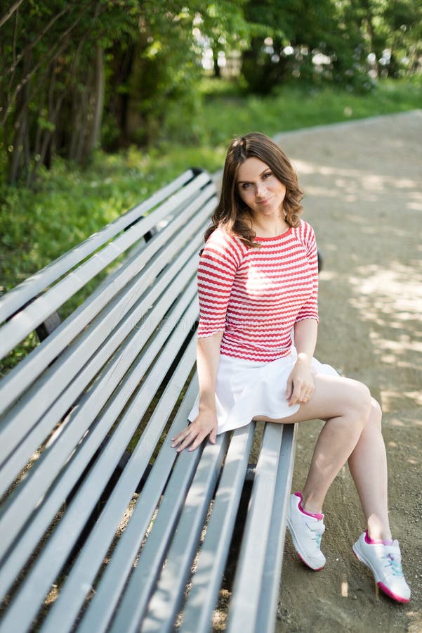 Brunette Fashion Model Sits on a Park Bench Stock Photo - Image of ...