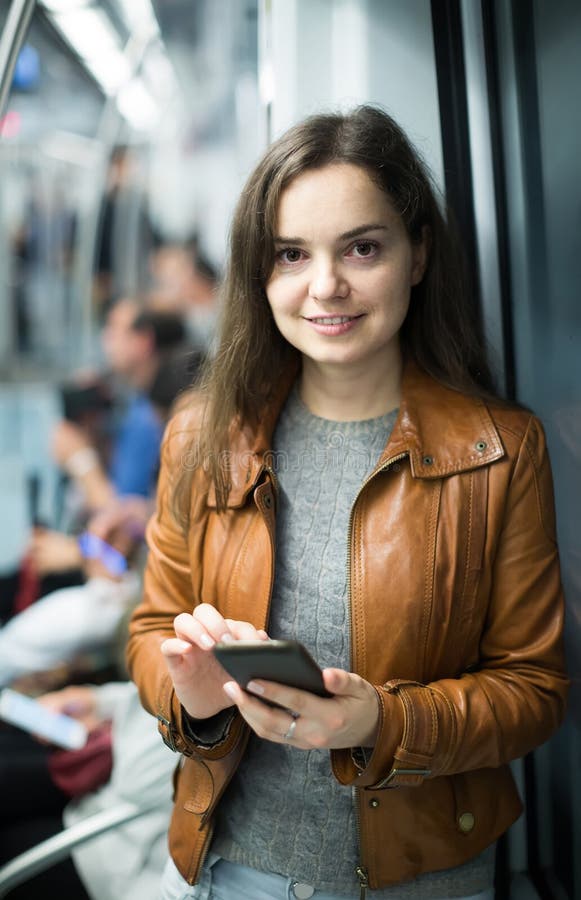 Brunette Girl Using Cell Phone and Smiling at Subway Stock Photo ...