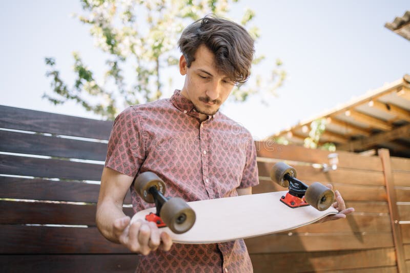 Brunette Man Holding Skateboard and Checking Wheels Stock Photo - Image ...