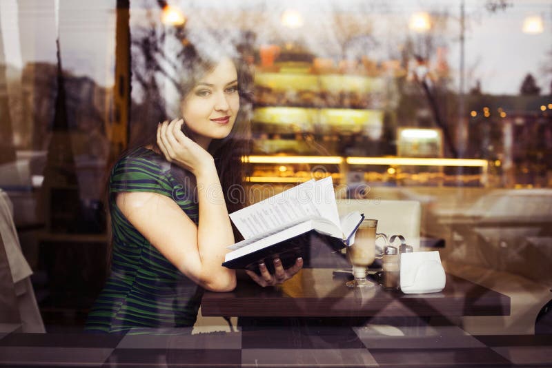 Brunette Woman Sitting at the Cafe Reading Book, Studing and Drinking ...
